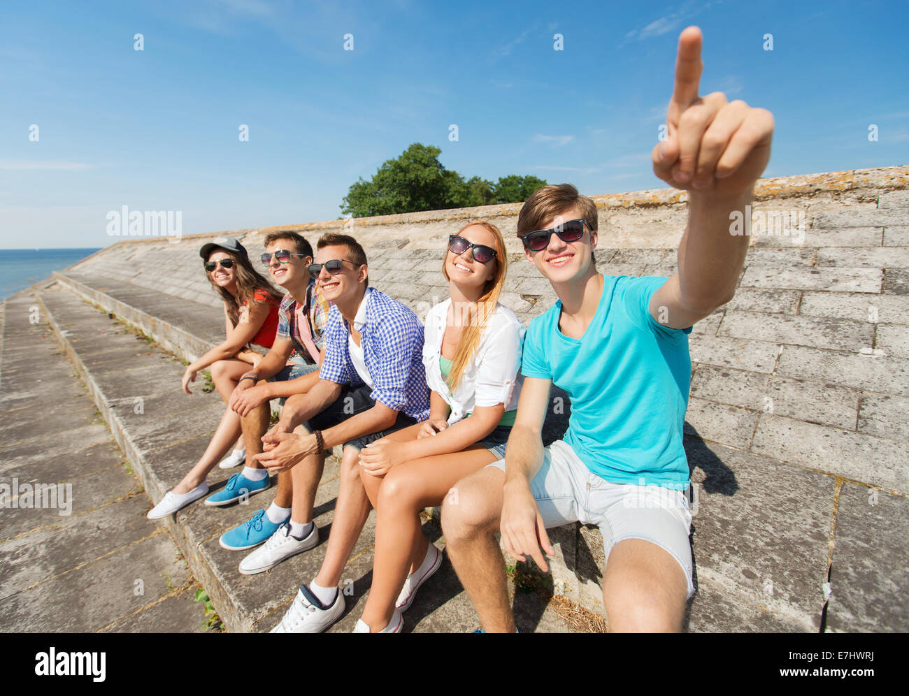 group of smiling friends sitting on city street Stock Photo - Alamy