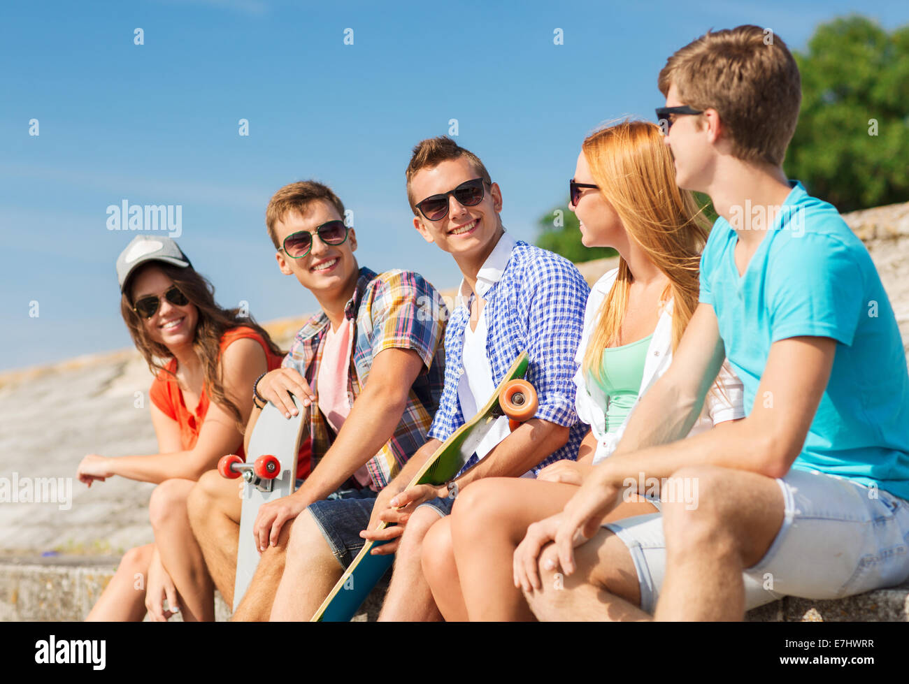 group of smiling friends sitting on city street Stock Photo - Alamy