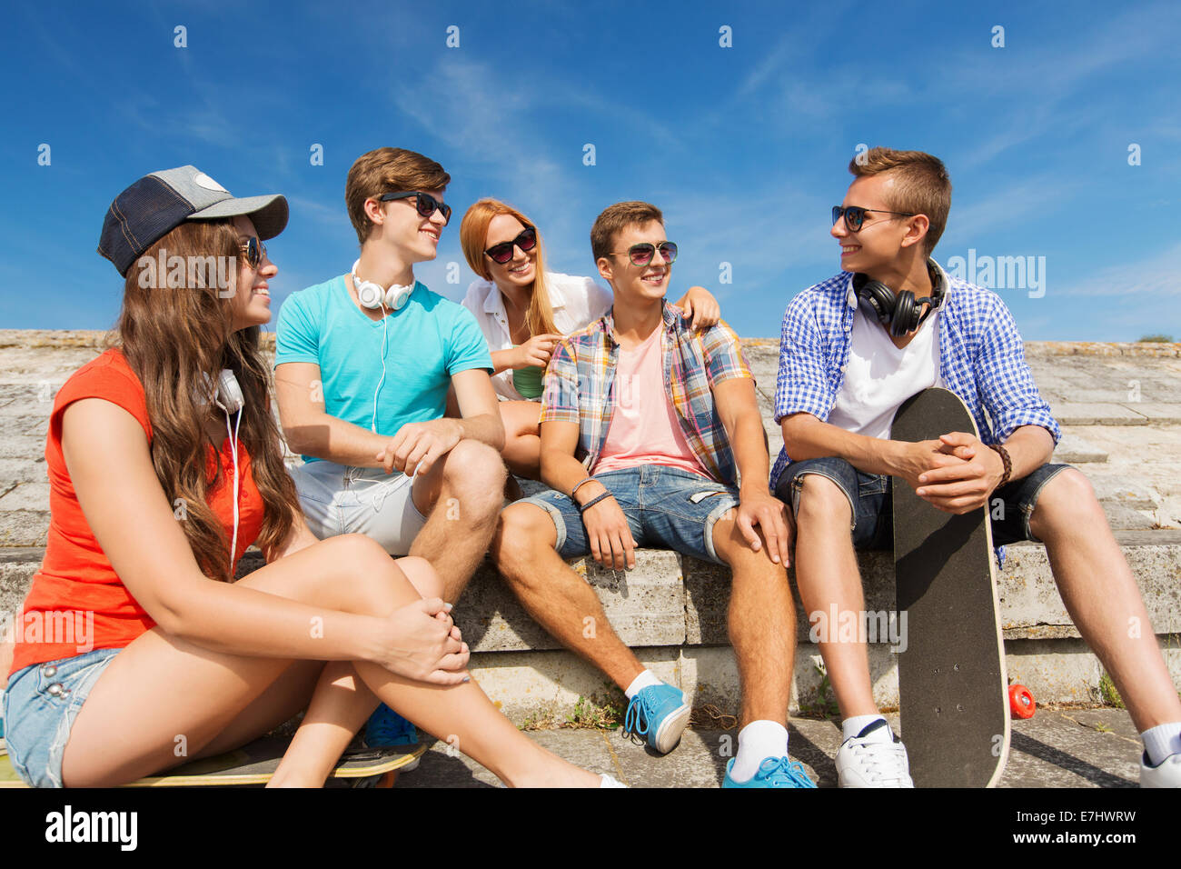 group of smiling friends sitting on city street Stock Photo - Alamy