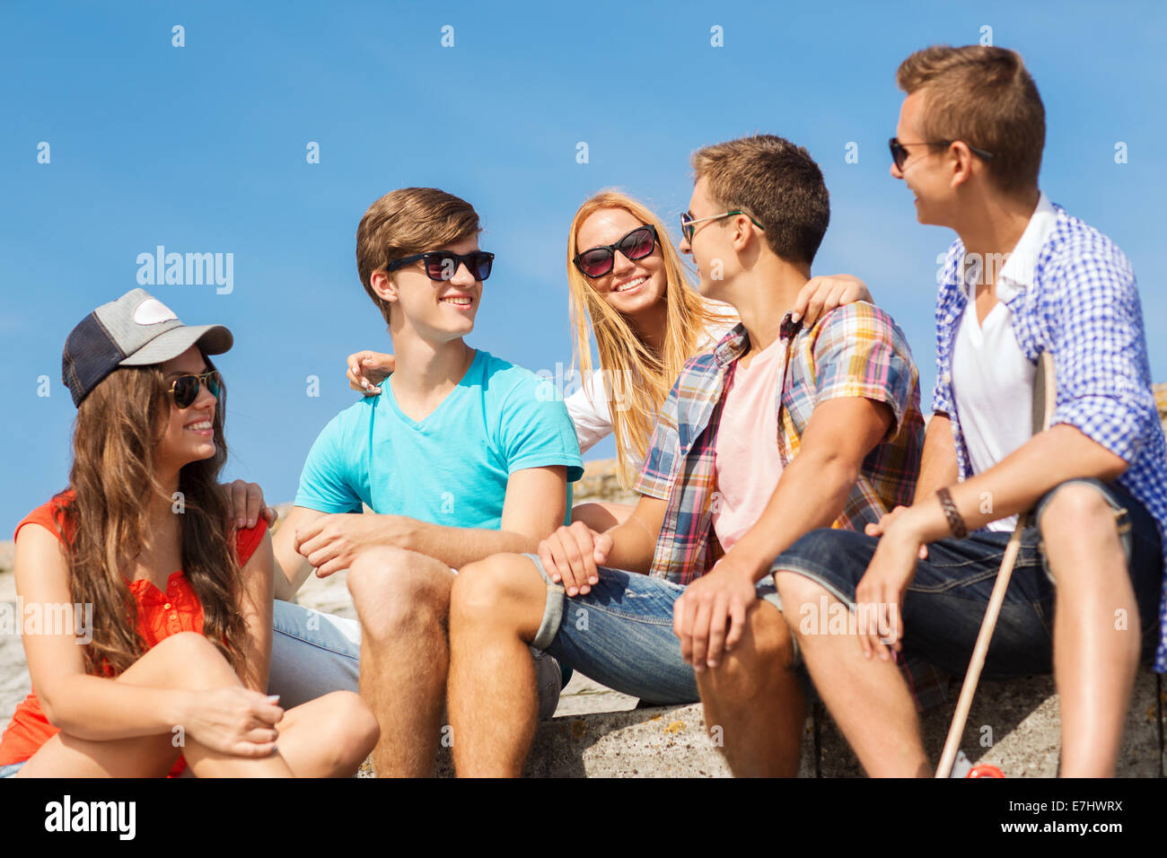 group of smiling friends sitting on city street Stock Photo - Alamy