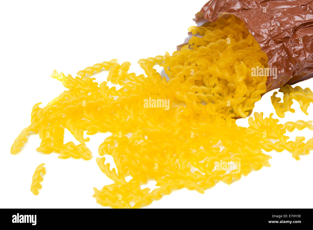 Curly pasta flowing from a bag over white background Stock Photo - Alamy