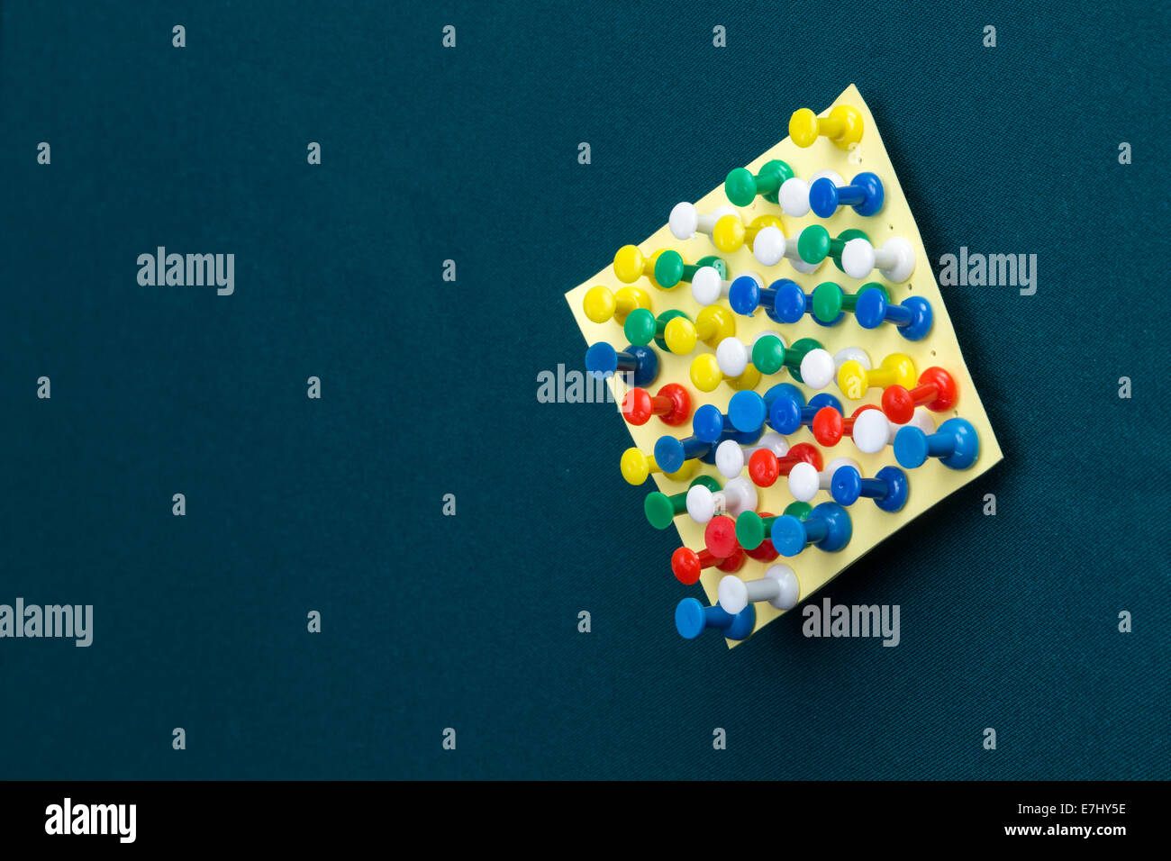Yellow post-it note with many push pins on a green board Stock Photo ...