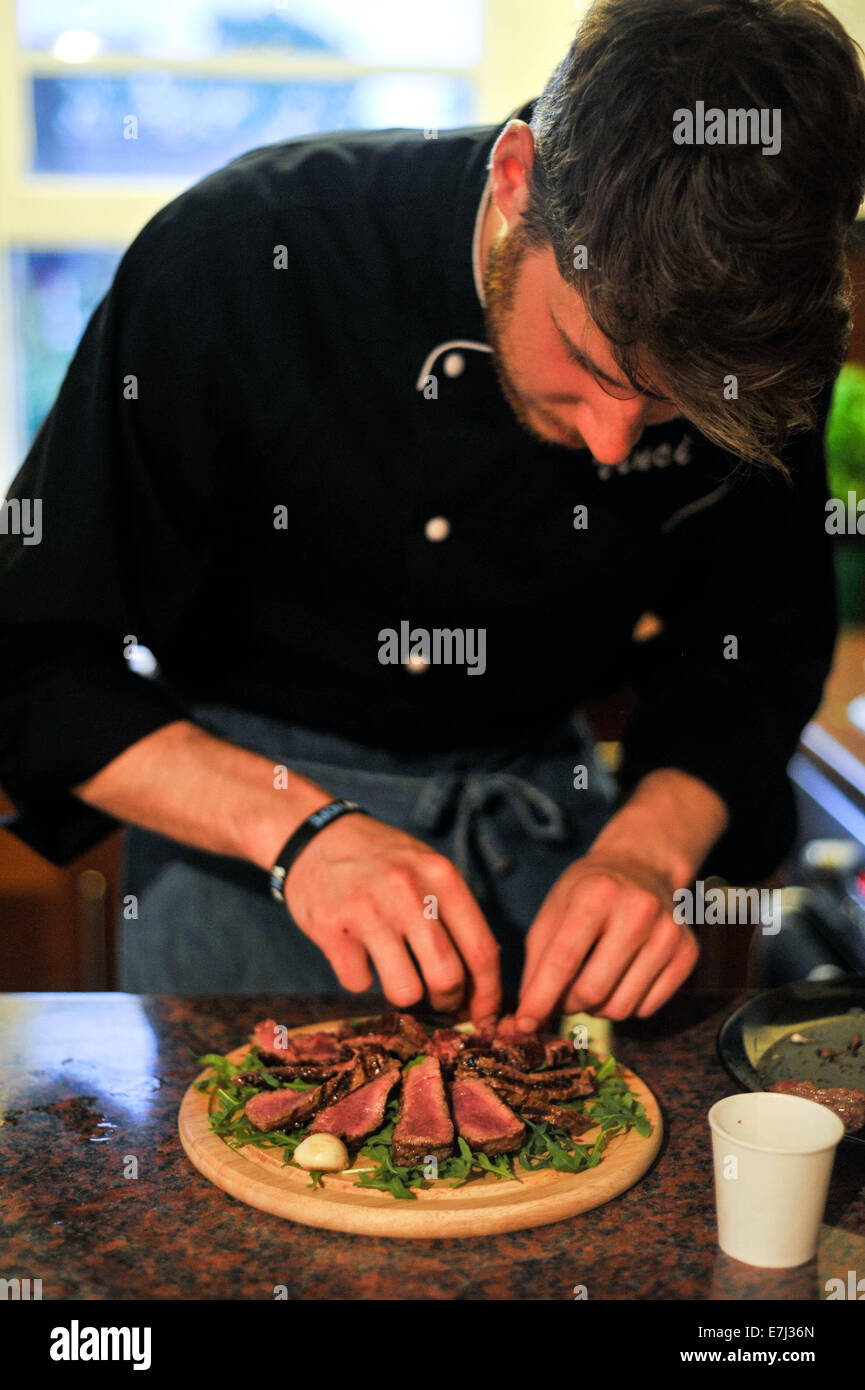 Young chef preparing a meat dish in a kitchen Stock Photo - Alamy