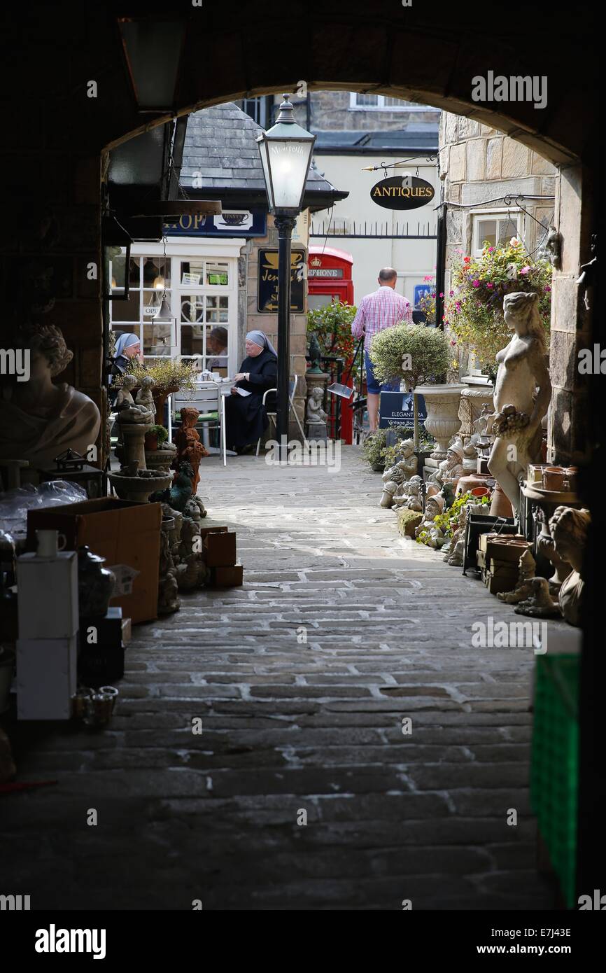 Two nuns sat enjoying tea at the café with lady walking through arch ...