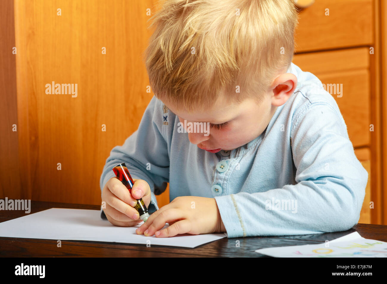 Happy childhood. Blonde boy child kid with pen writing drawing on paper ...