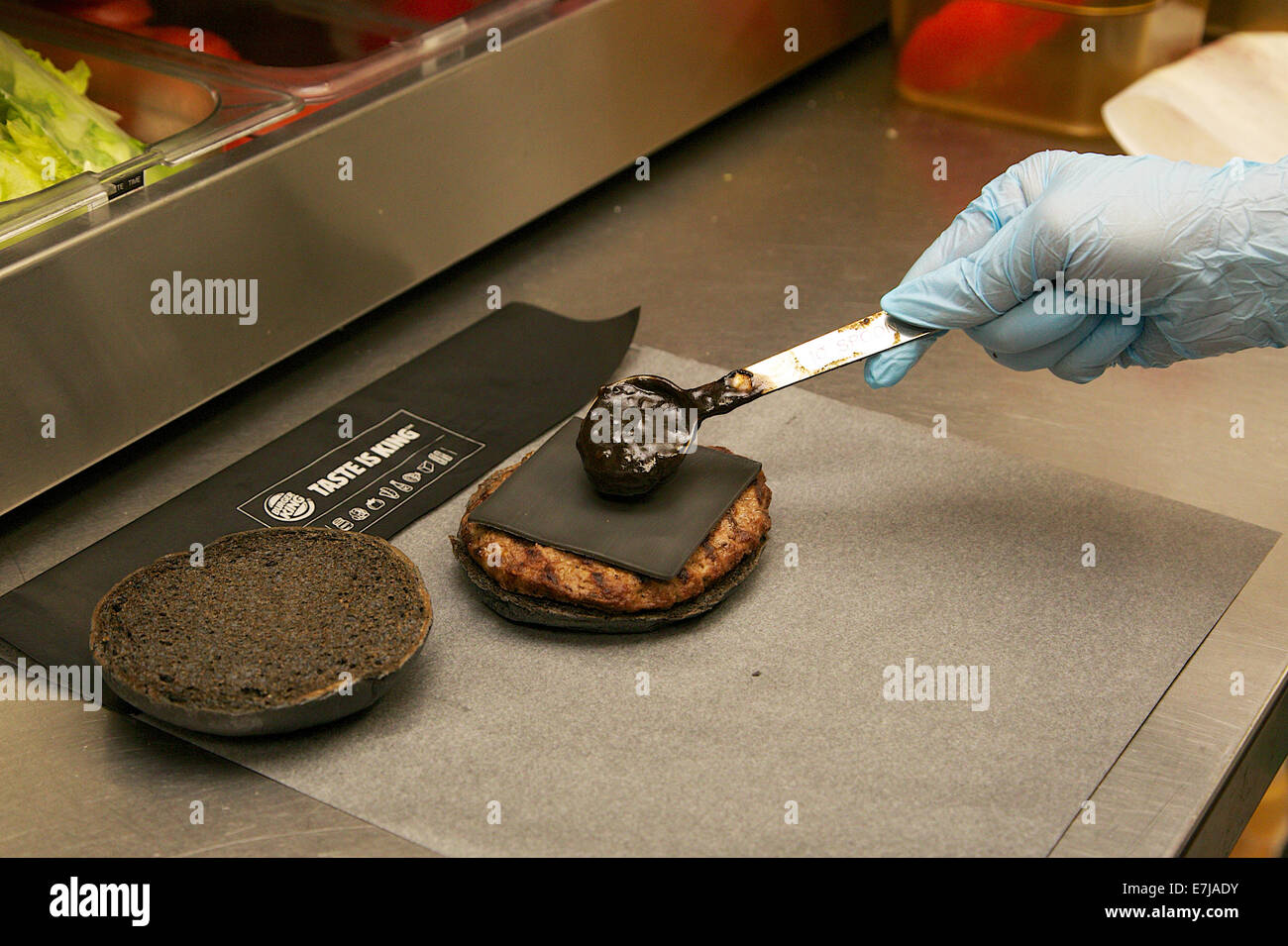 Tokyo, Japan. 19th Sep, 2014. A woman prepares a "kuro burger" or ...