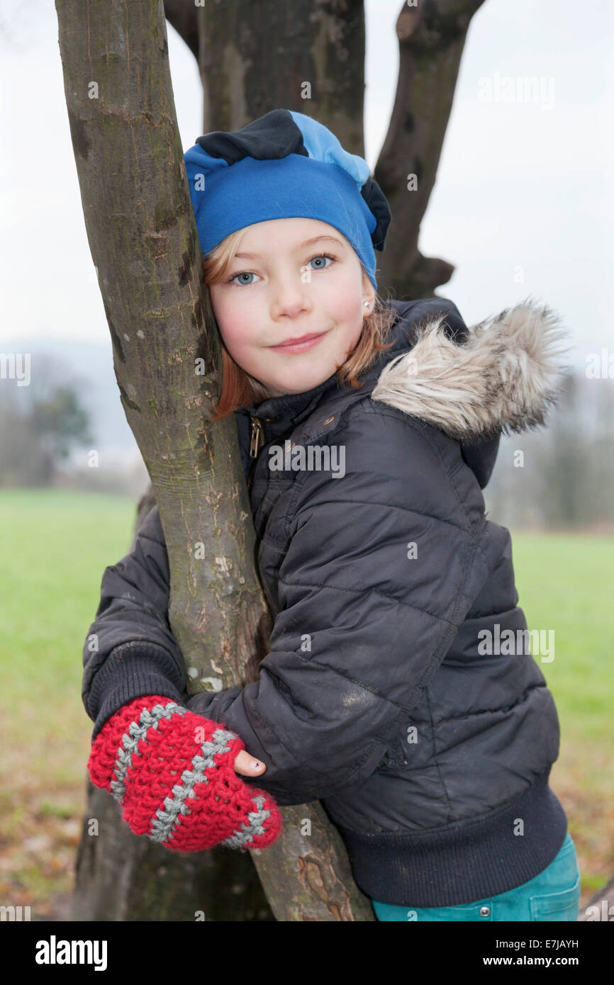 Girl, 9, wearing a hat and gloves, on a tree Stock Photo - Alamy