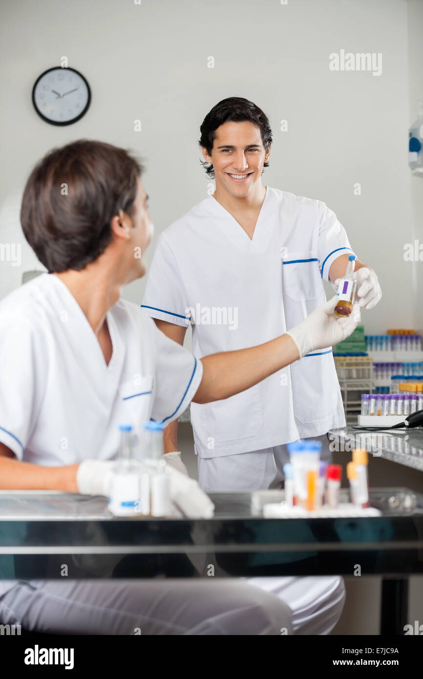 Technician Handing Over Sample To Colleague Stock Photo - Alamy