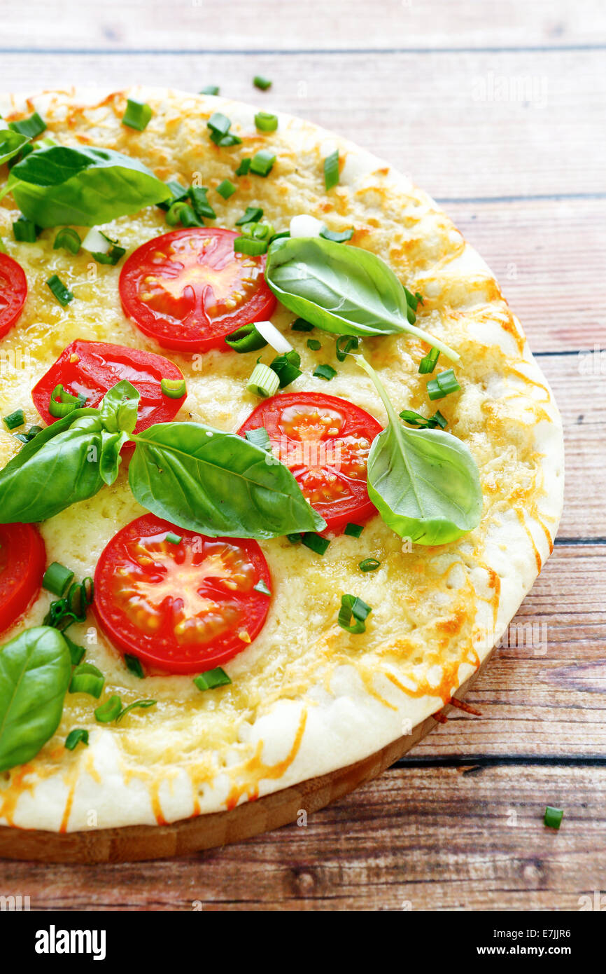 Pizza with cheese tomatoes and greens, side view Stock Photo - Alamy
