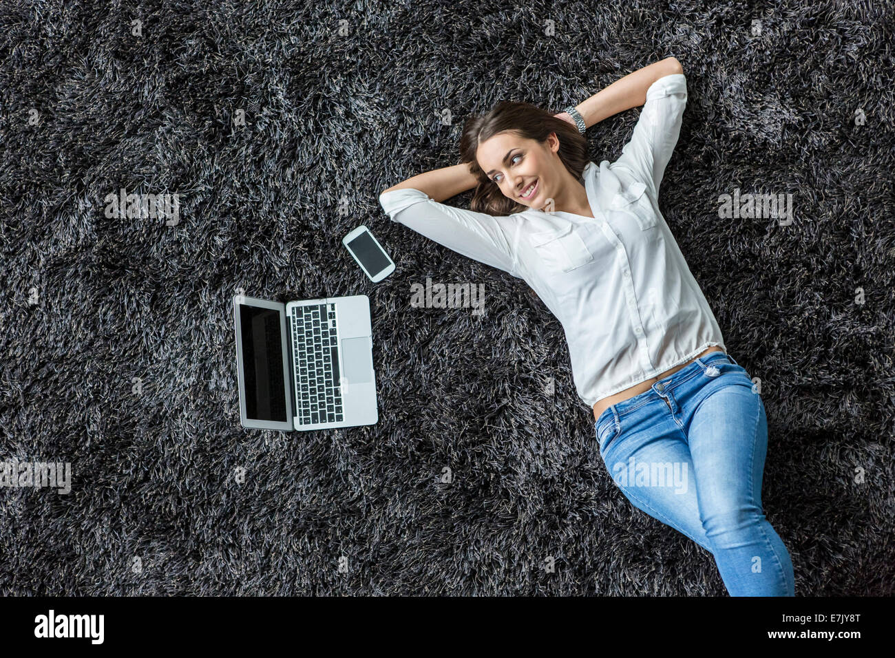 Young woman laying on the carpet Stock Photo - Alamy