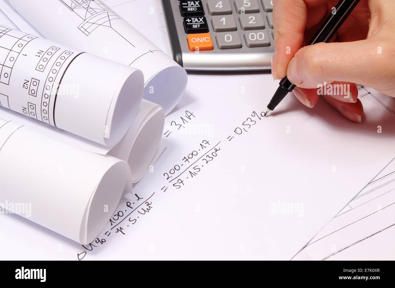 Hand of woman performing mathematical calculations for project, rolled ...