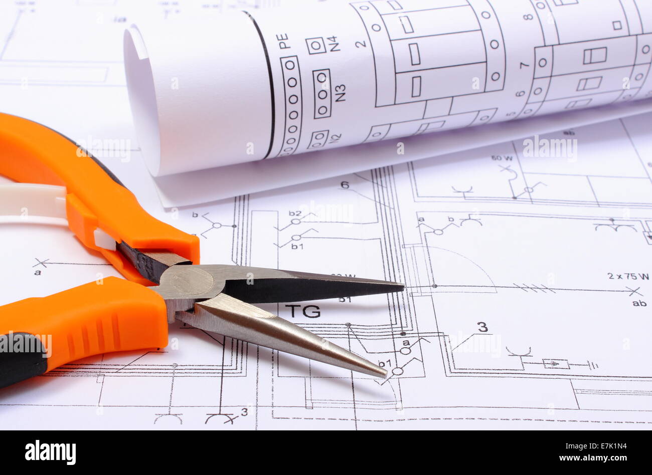 Orange metal pliers with rolled electrical diagram lying on ...