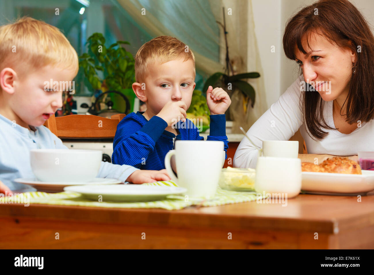 Happy family. Mother and sons boys kids children eating corn flakes and ...
