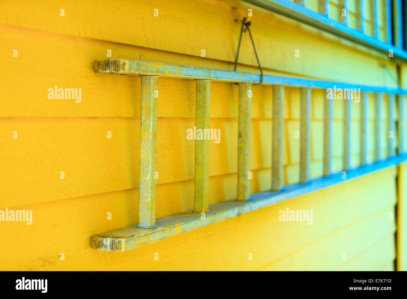 Wooden old ladder hanging on yellow house wall Stock Photo - Alamy