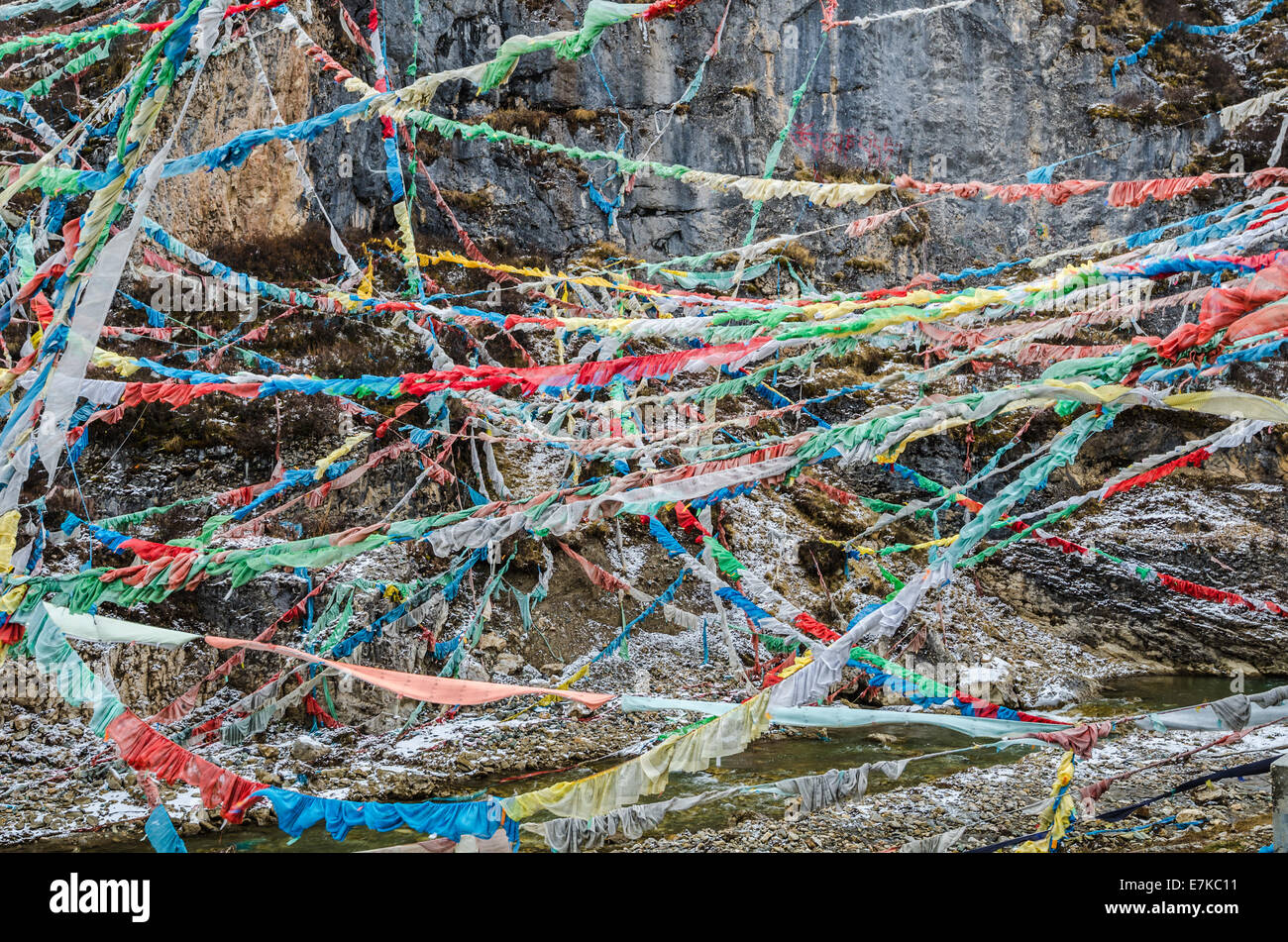 Colorful prayer flags are waving above the river at a mountain pass ...