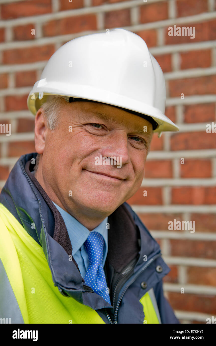 Portrait of a smiling building contractor wearing a white safety helmet ...