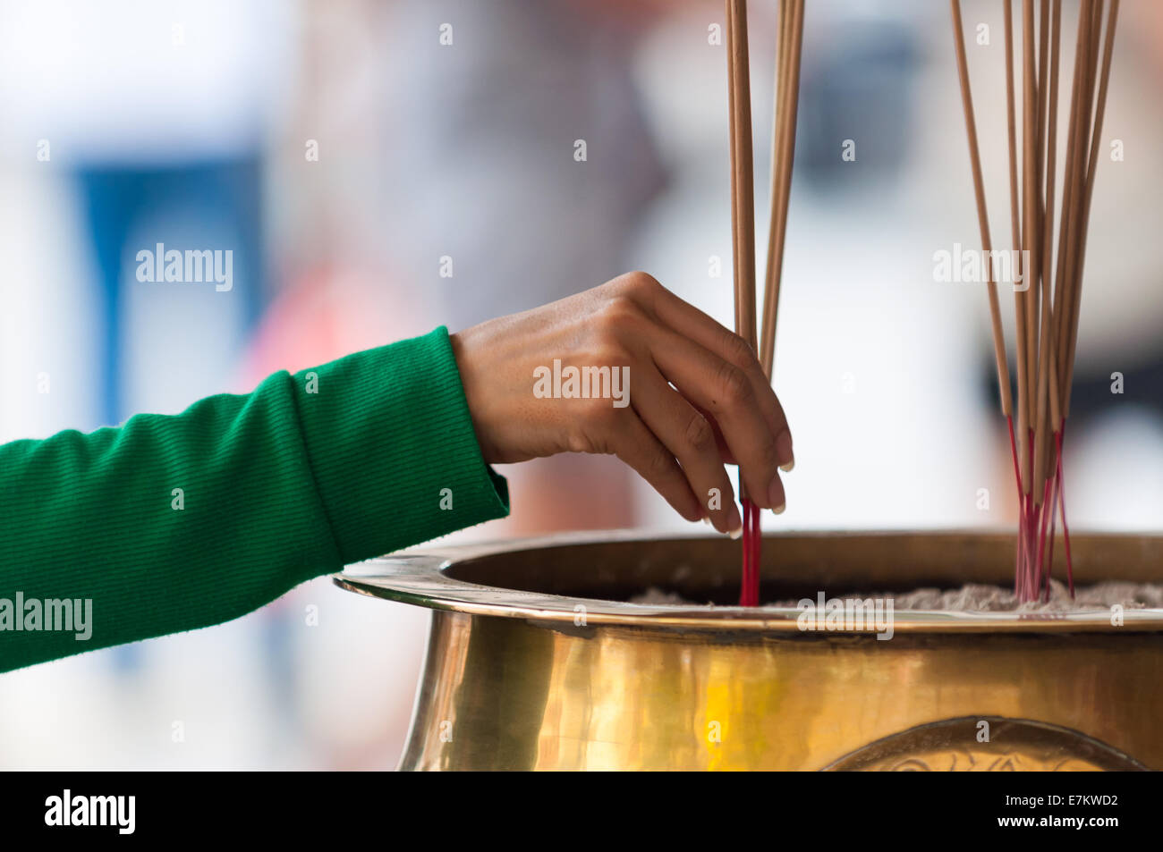 A female hand places a stick of incense in a large pot at Sri Krishnan ...