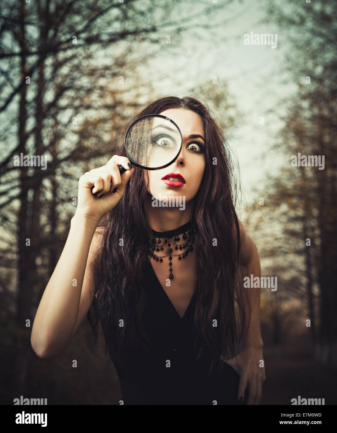 The strange goth girl looks through a loupe Stock Photo - Alamy
