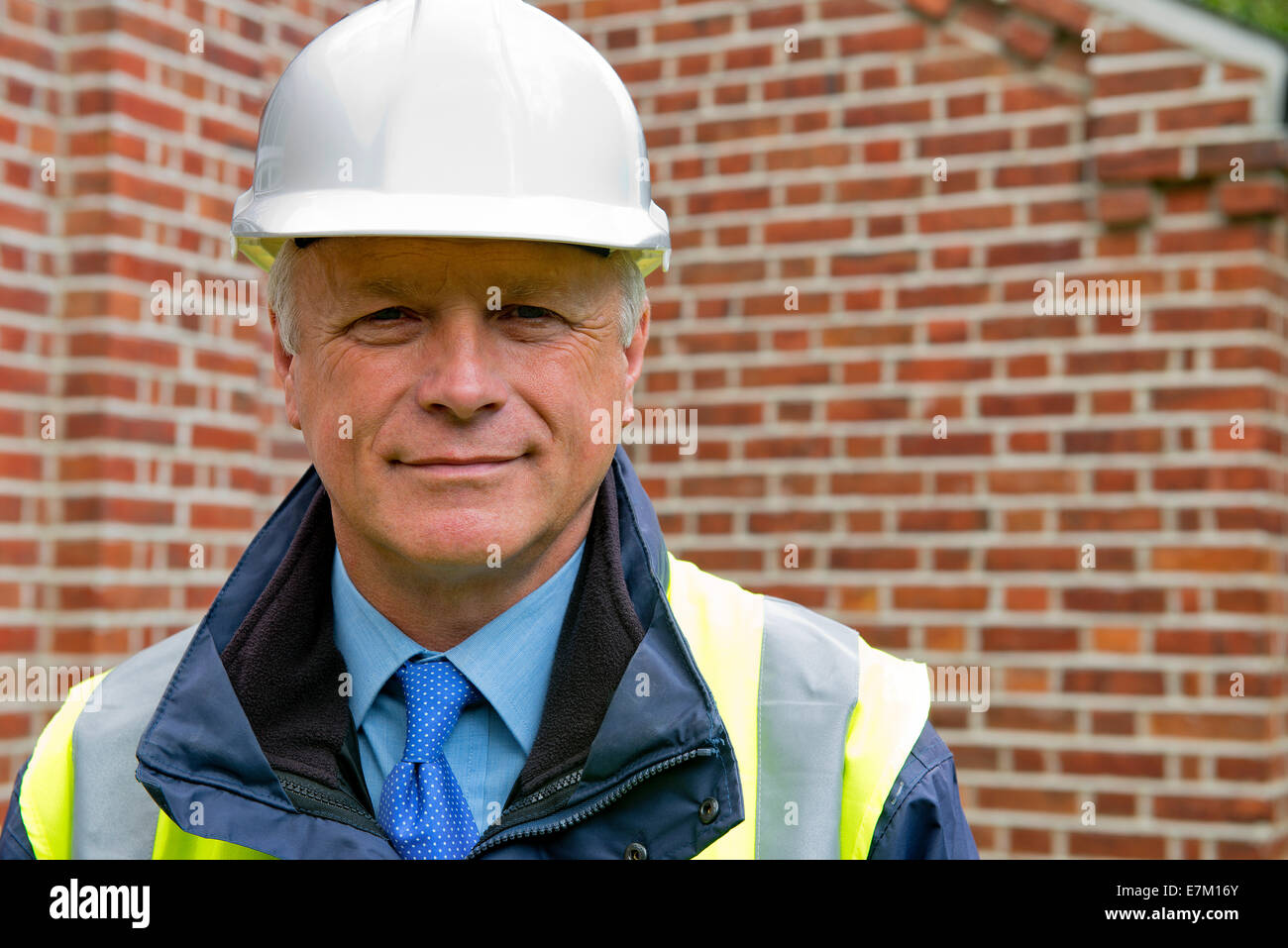 Head and shoulders view of a maintenance engineer against a brick wall ...