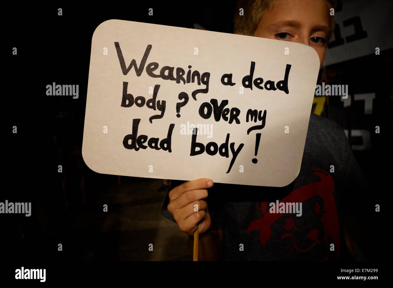 A demonstrator holds a cardboard sign which reads "Wearing a dead body ...