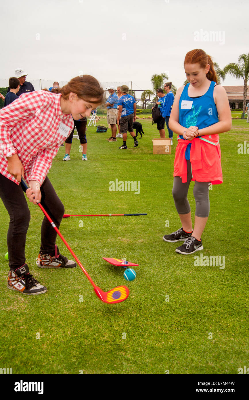 A blind teen girl hits a Snag Golf oversize ball as a young volunteer ...