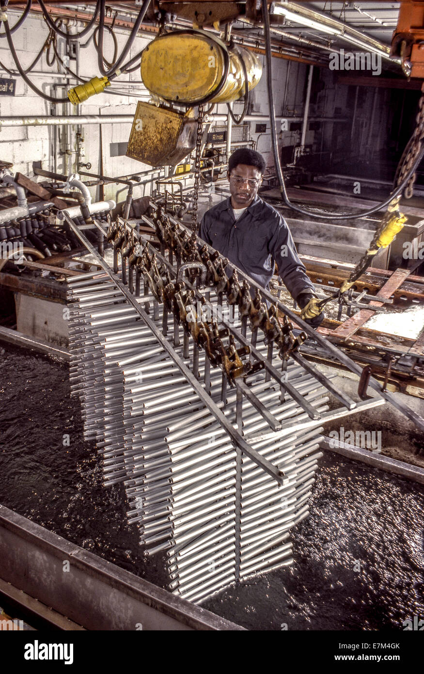 Using an electric hoist, an African American technician lifts aluminum ...