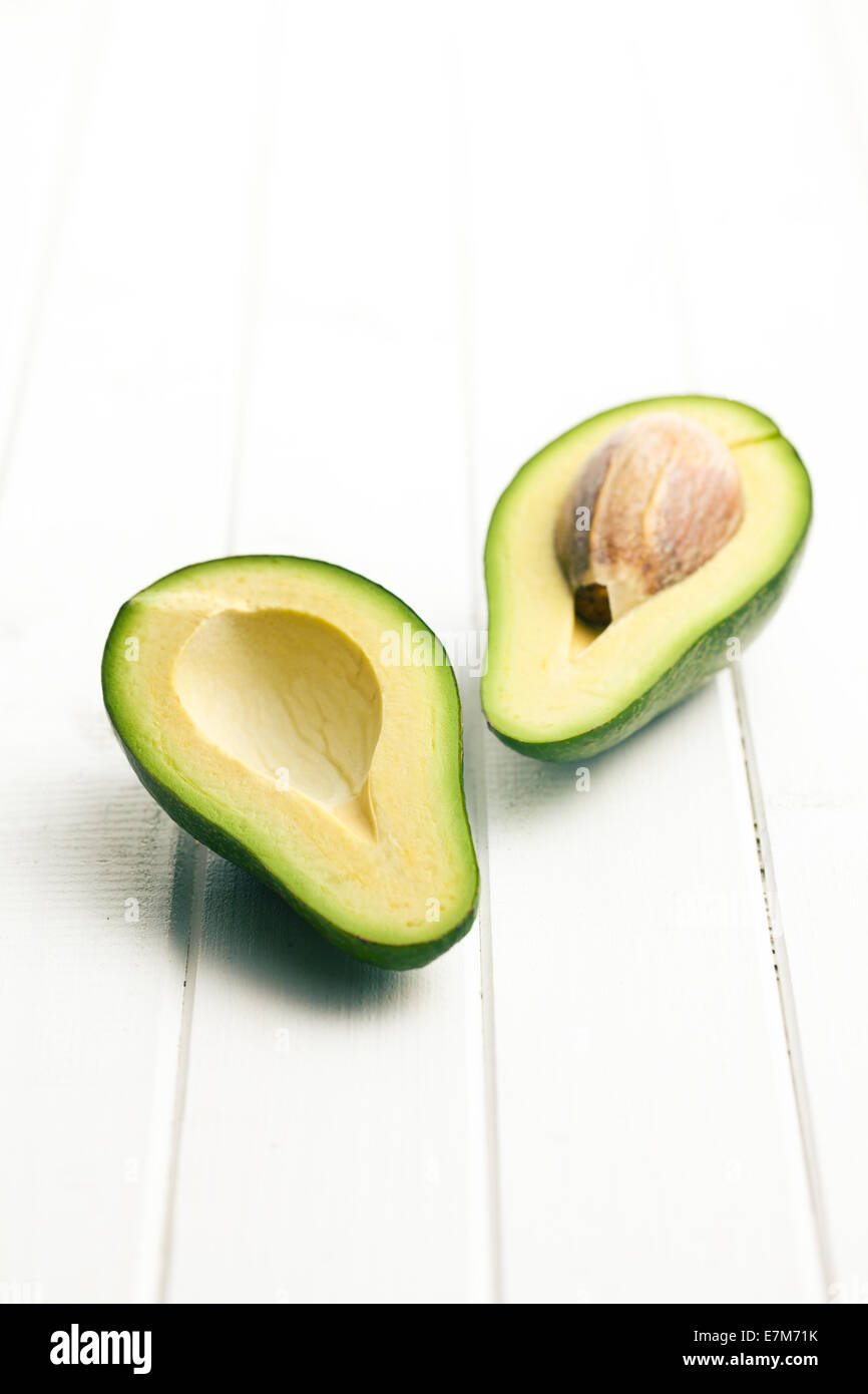 halved avocados on white wooden table Stock Photo - Alamy