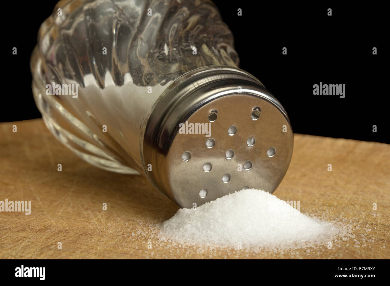 Split salt and salt shaker on wood with black background Stock Photo ...