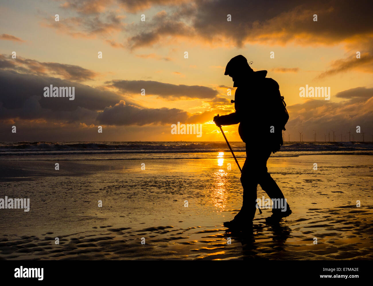 A female walker on Seaton Carew beach at sunrise, setting out on the ...