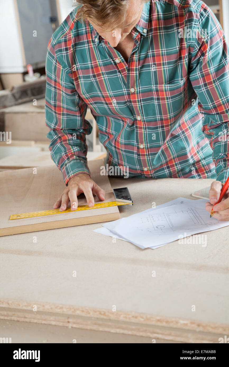 Carpenter Working On Blueprint While Measuring Wood Stock Photo - Alamy