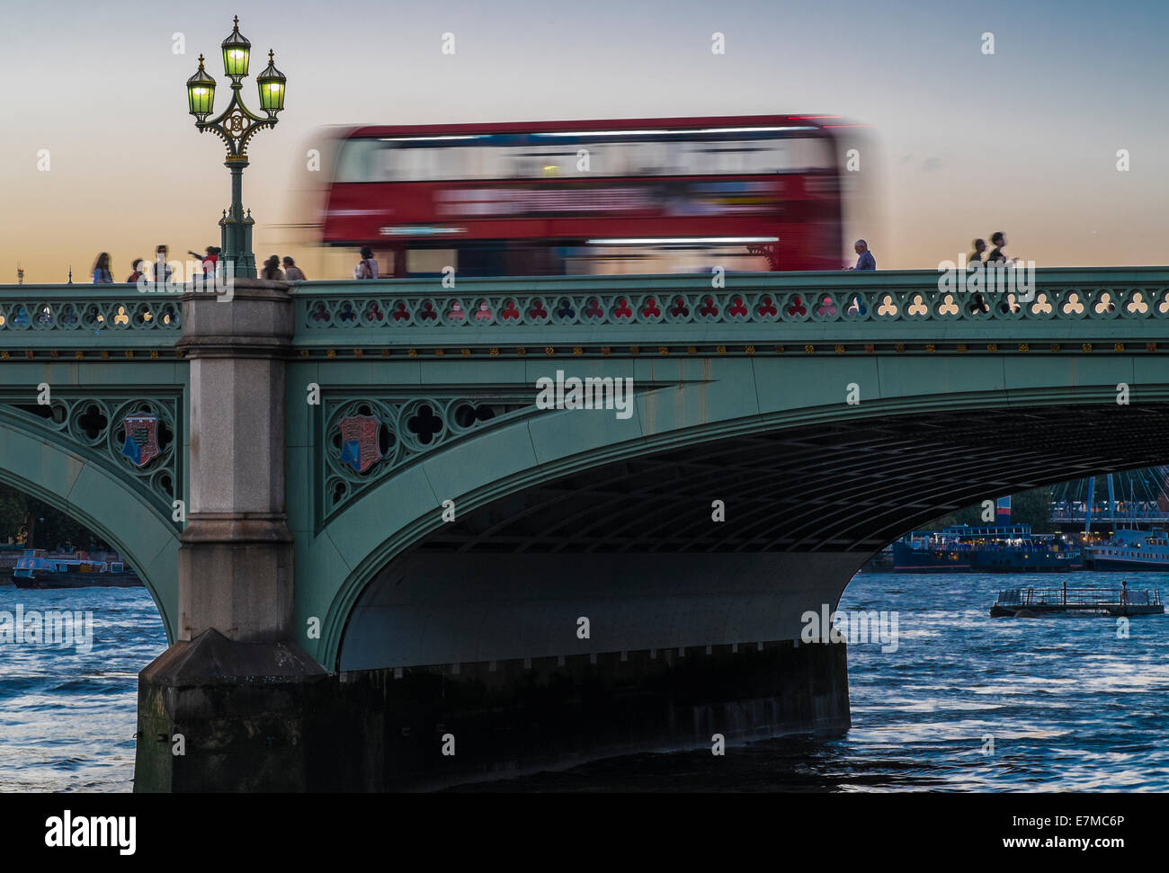 A red London bus speeds across Westminster Bridge in the summers ...