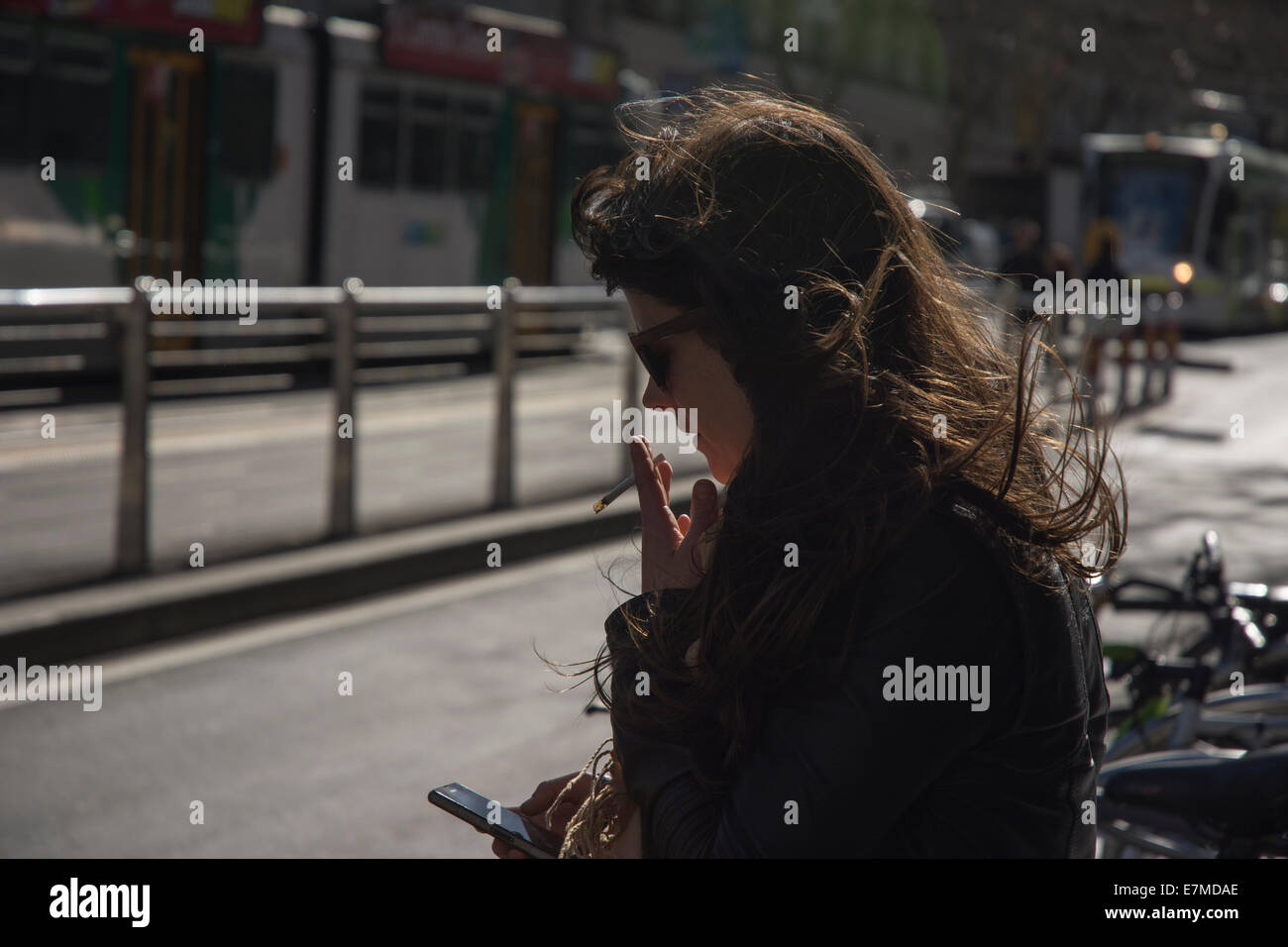 Young Woman Smoking While Looking At Her Phone Stock Photo - Alamy