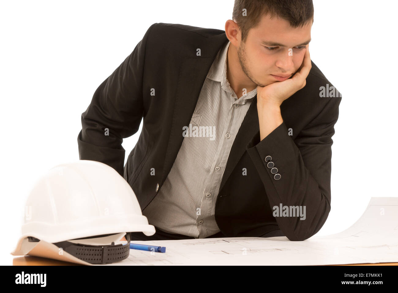 Young engineer, builder or architect sitting with his chin resting on ...