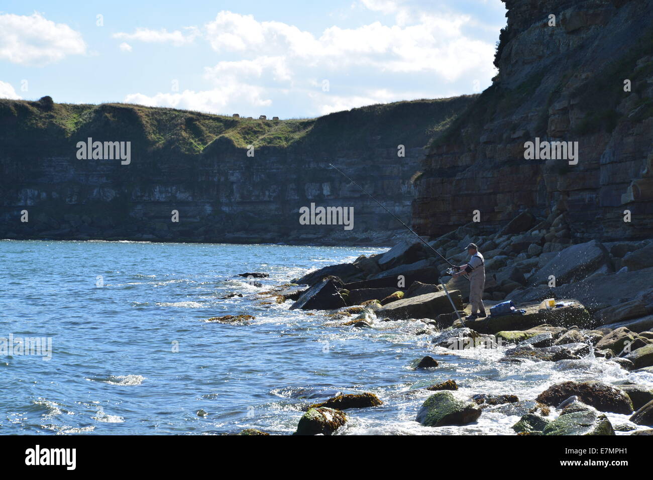 Man fishing on rocks in cove Stock Photo - Alamy