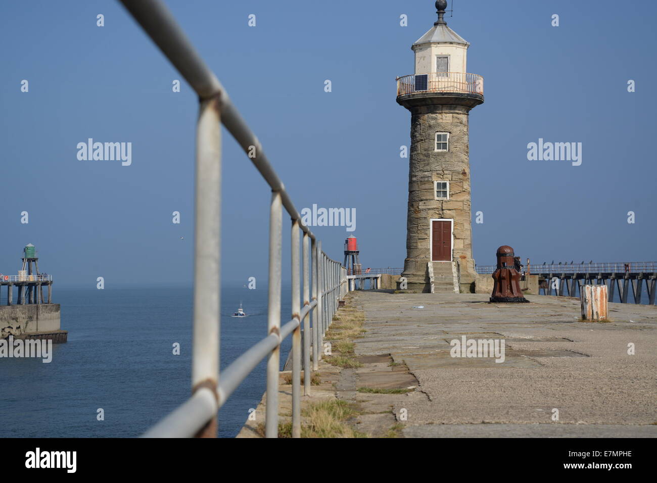 Whitby lighthouse with fishing boat coming into harbour between ...