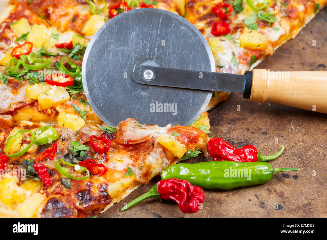 Closeup view of cutting wheel separating slice of freshly baked pizza ...