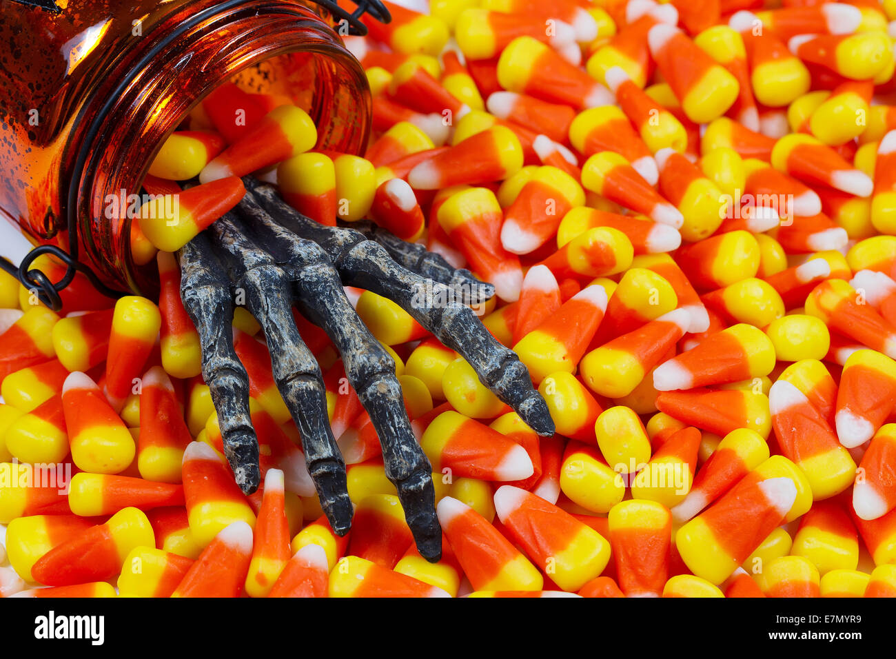 Closeup image of a scary hand coming out of jar into pile of candy corn ...