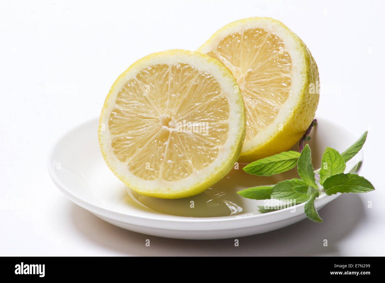 Fresh lemon cut in halves and mint sprig on white background Stock ...
