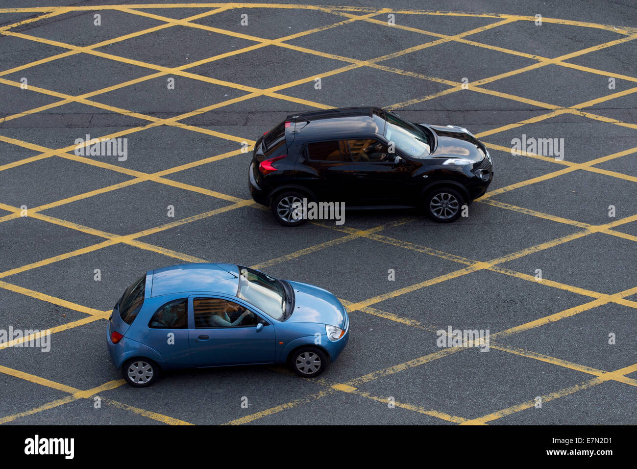 Two cars drive through a yellow box junction in Cardiff, South Wales ...