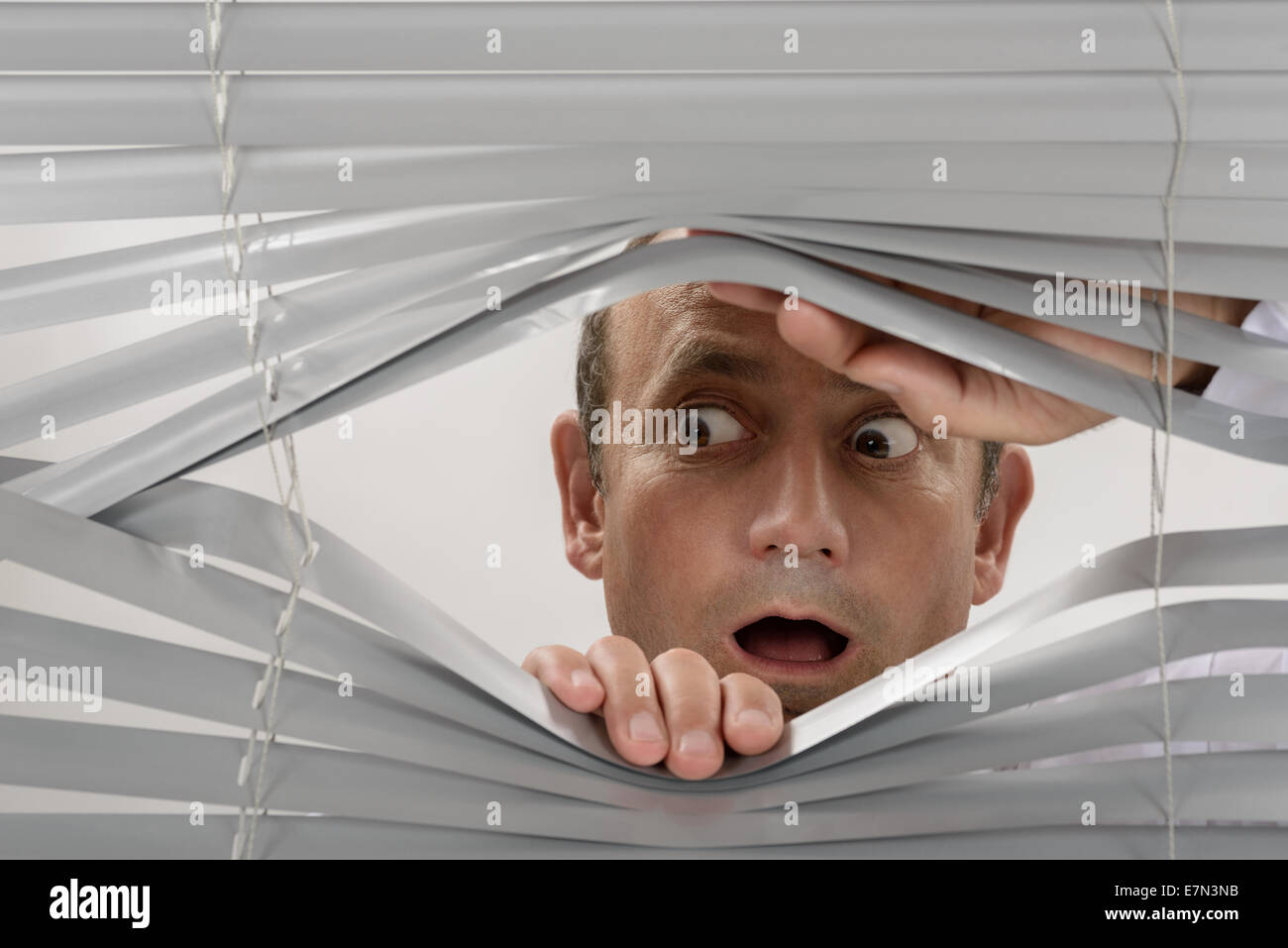 Shocked man watching out of window Stock Photo - Alamy