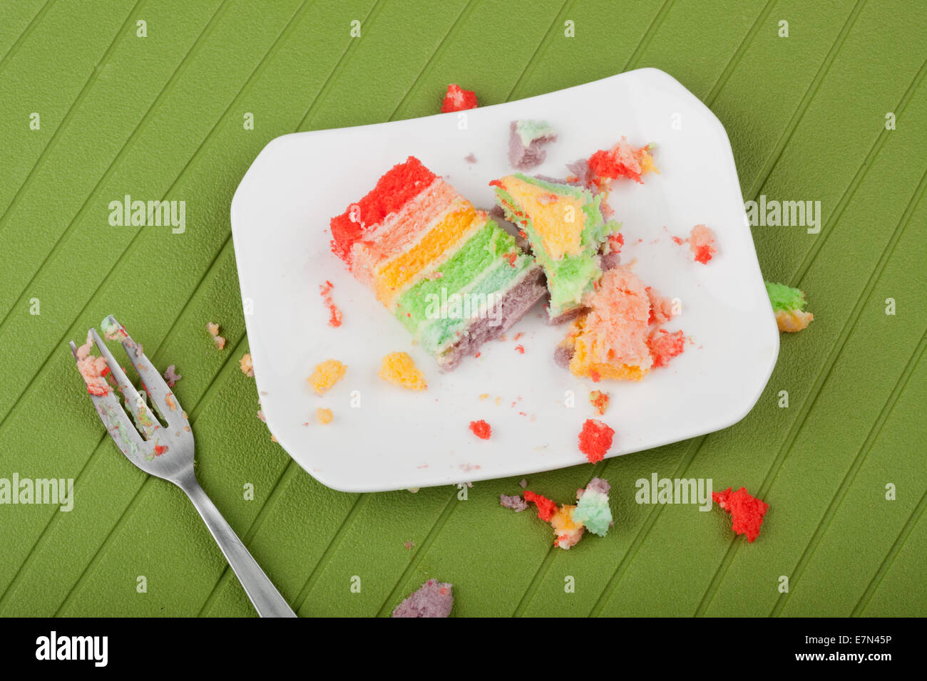 Messy leftover rainbow cake on a plate with crumbs around it Stock ...