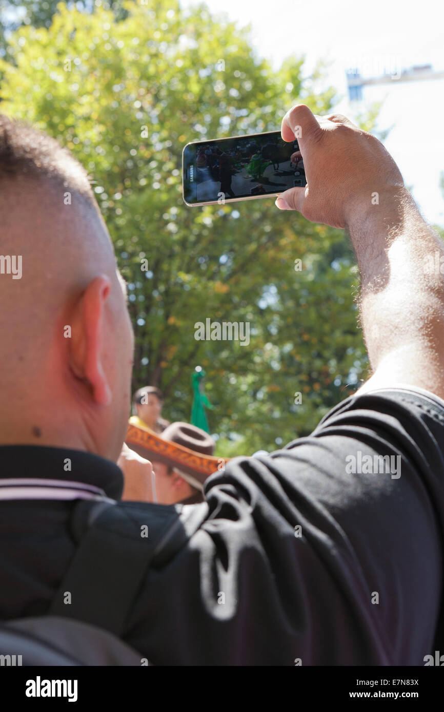 Man capturing video of event at an outdoor festival with smart phone ...