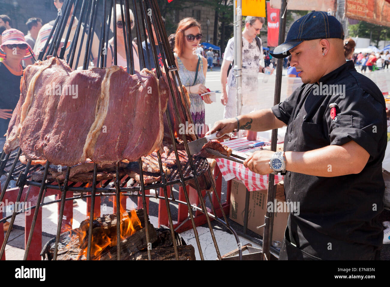 Man cooking beef steaks on a large hanging barbecue grill - USA Stock ...