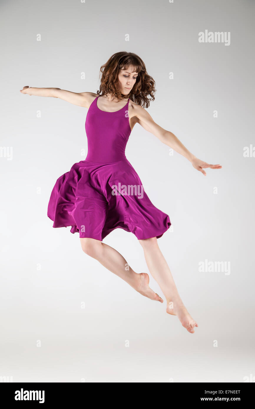 Young ballet dancer wearing purple dress over grey Stock Photo - Alamy