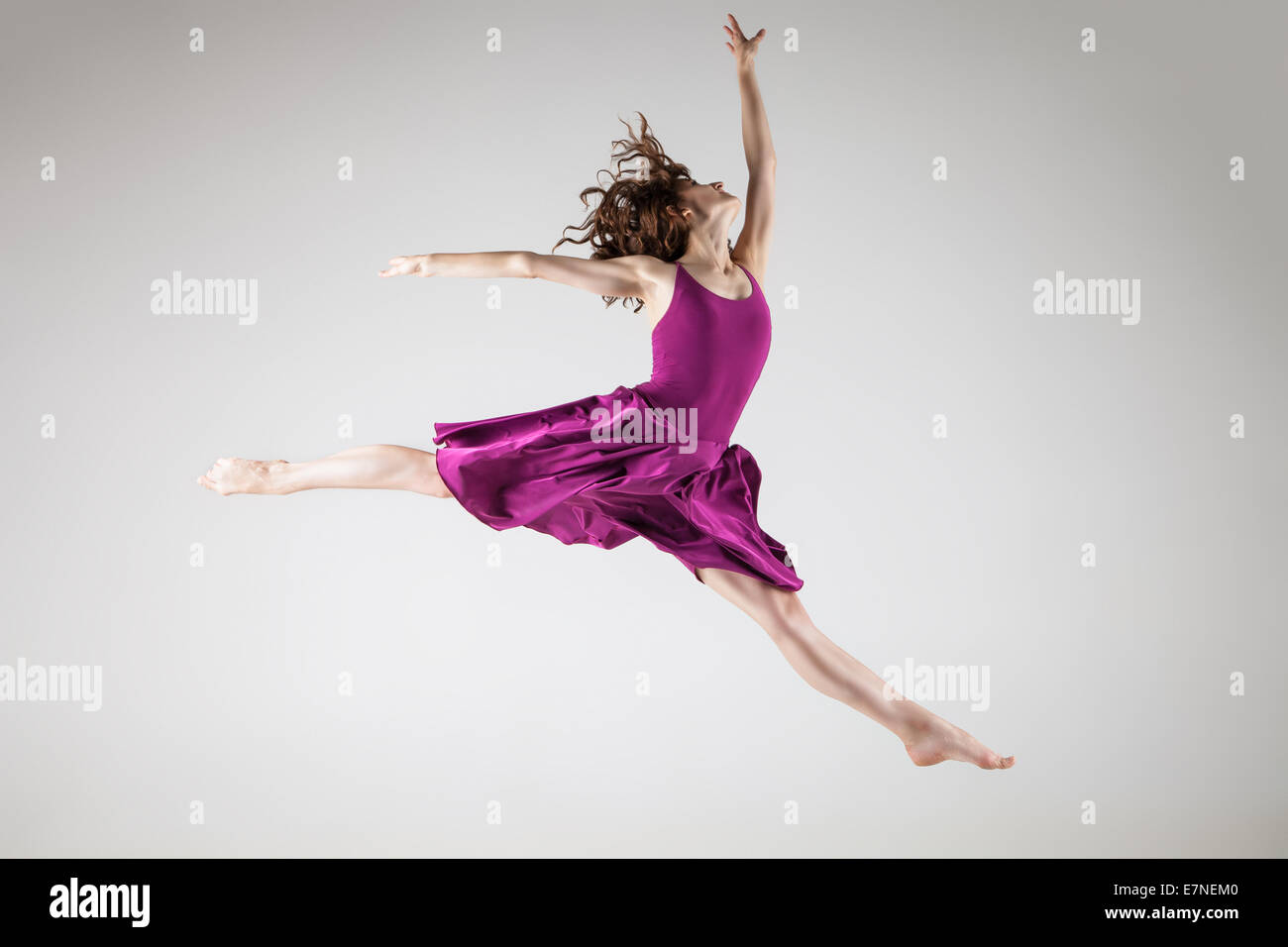 Young ballet dancer wearing purple dress over grey Stock Photo - Alamy