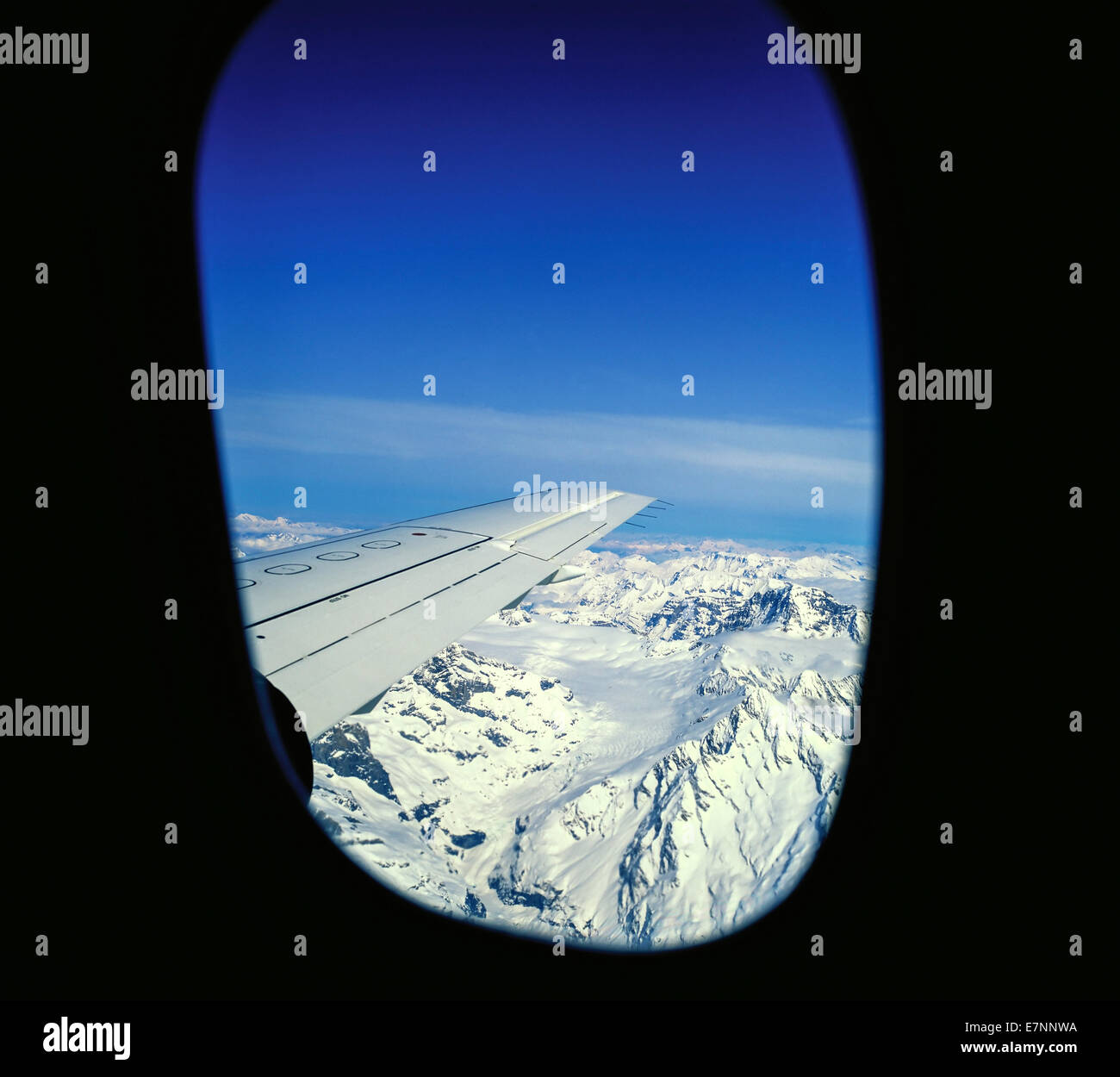 Aerial view of snowy Alps mountains through airplane window Switzerland ...