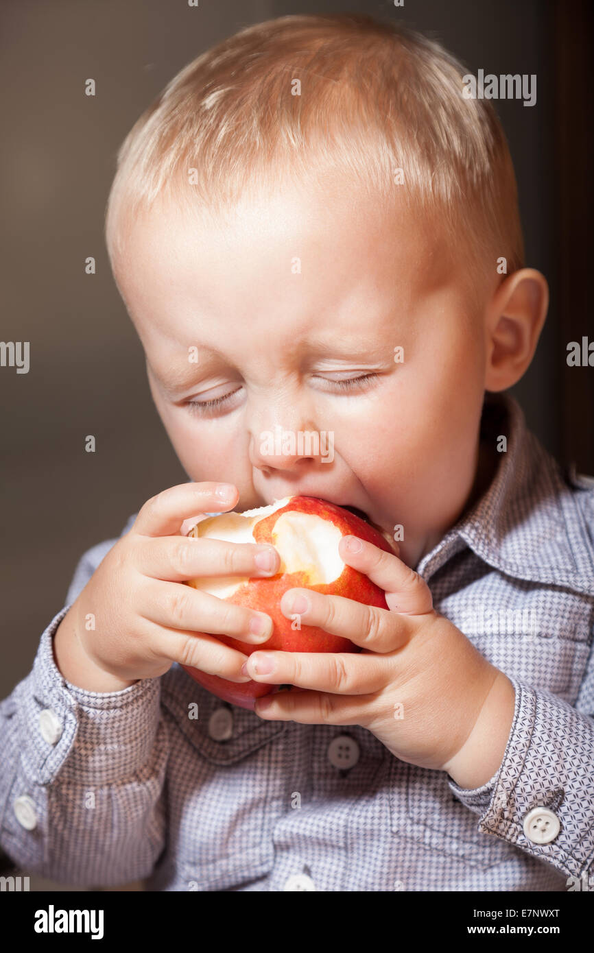 Happy childhood. Portrait of cute little boy child kid eating apple ...
