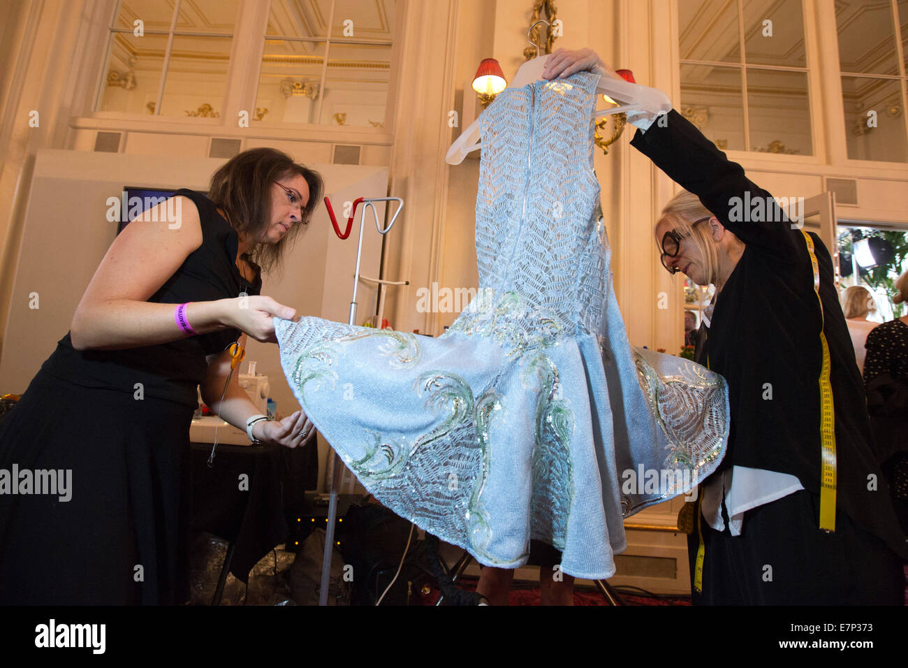 Two seamstresses prepare a dress for the show. Backstage before the ...