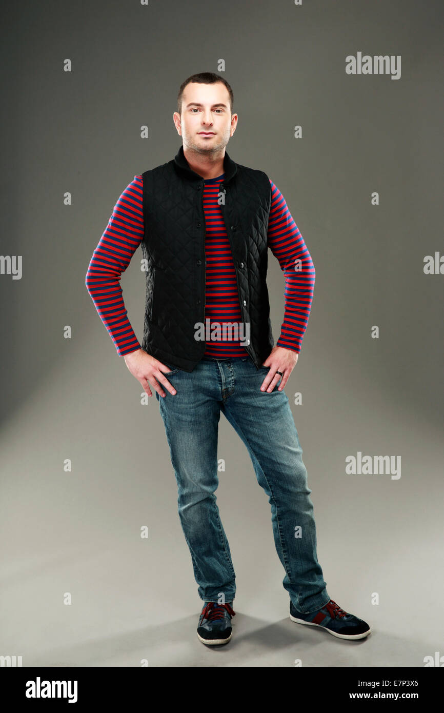 Full length portrait of a handsome man standing over gray background ...