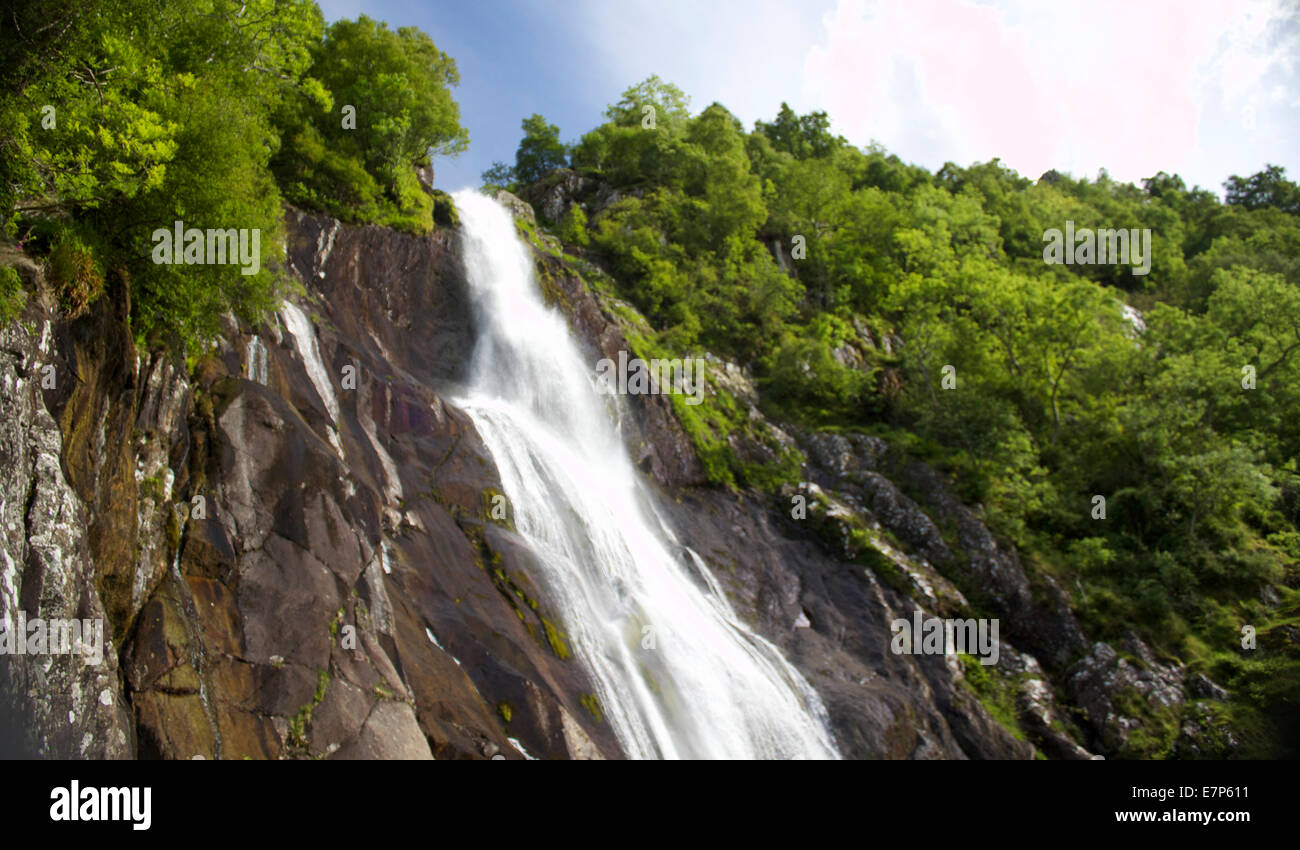 Waterfall over rocks between trees with sky in the background Stock ...